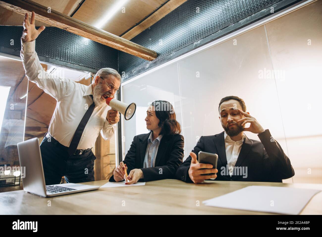 Scream. Angry boss with megaphone screaming at employees in office ...