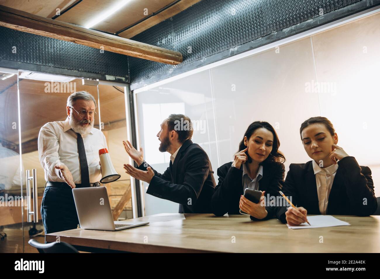 Talks. Angry boss with megaphone screaming at employees in office ...