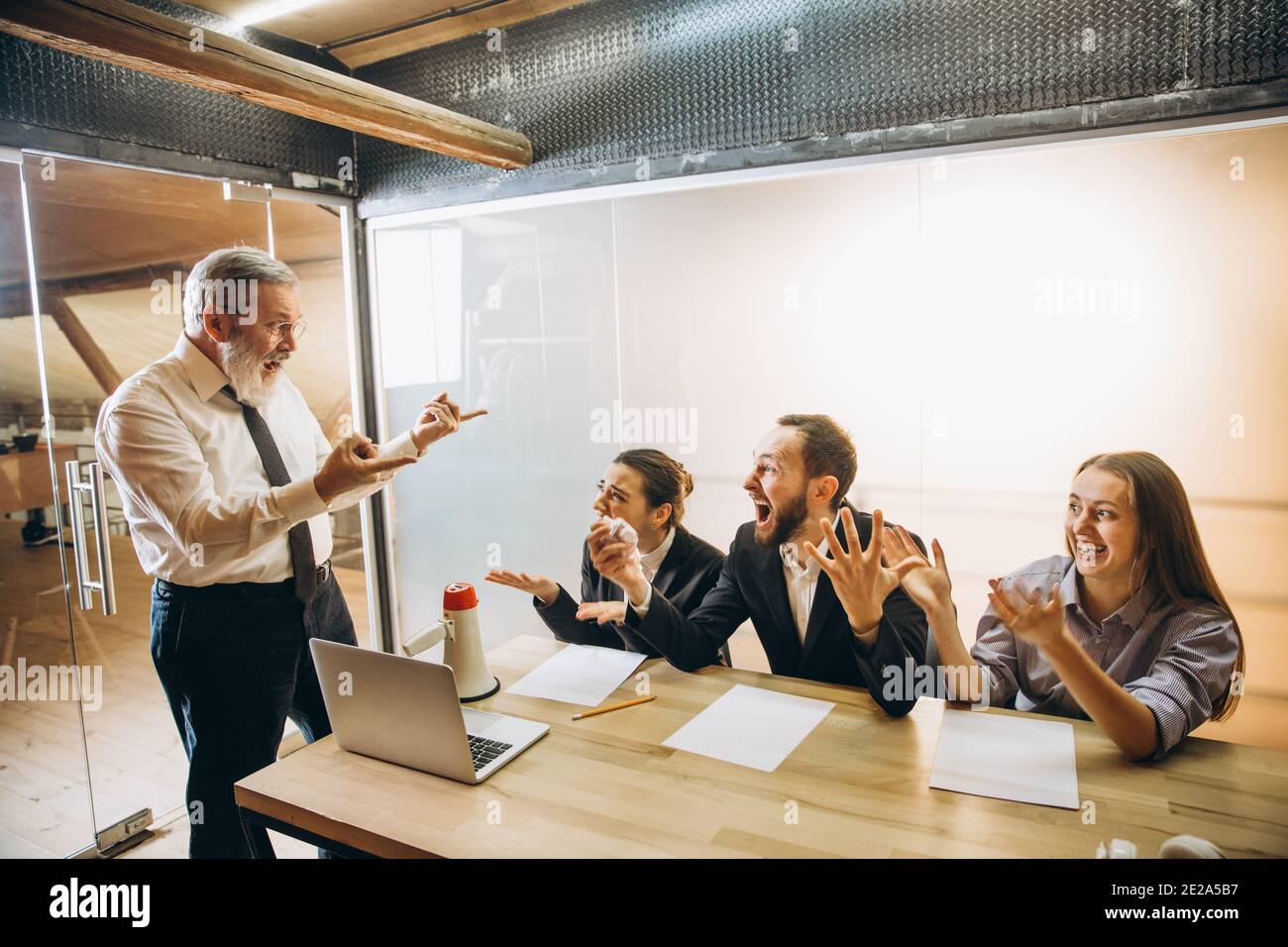 Scary. Angry boss with megaphone screaming at employees in office ...