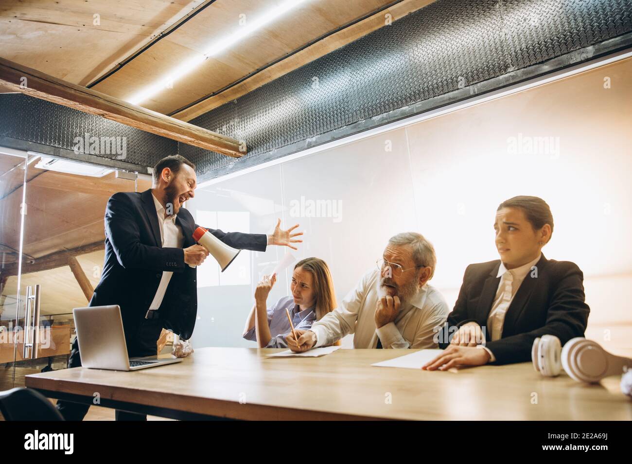 Shouting. Angry boss with megaphone screaming at employees in office ...