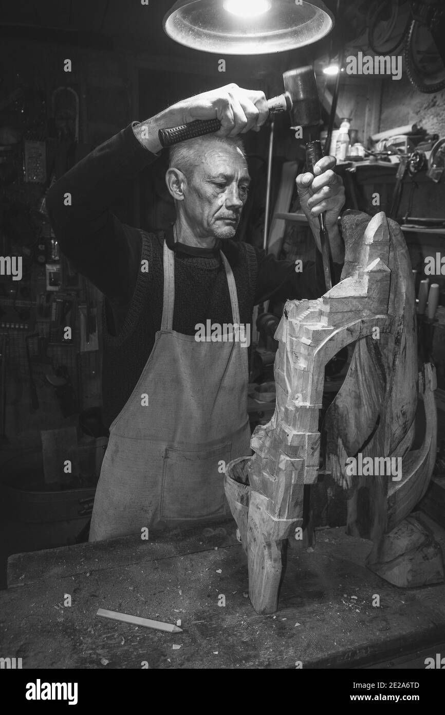 master carpenter 50 - 55 years old creates wooden sculpture in the ...