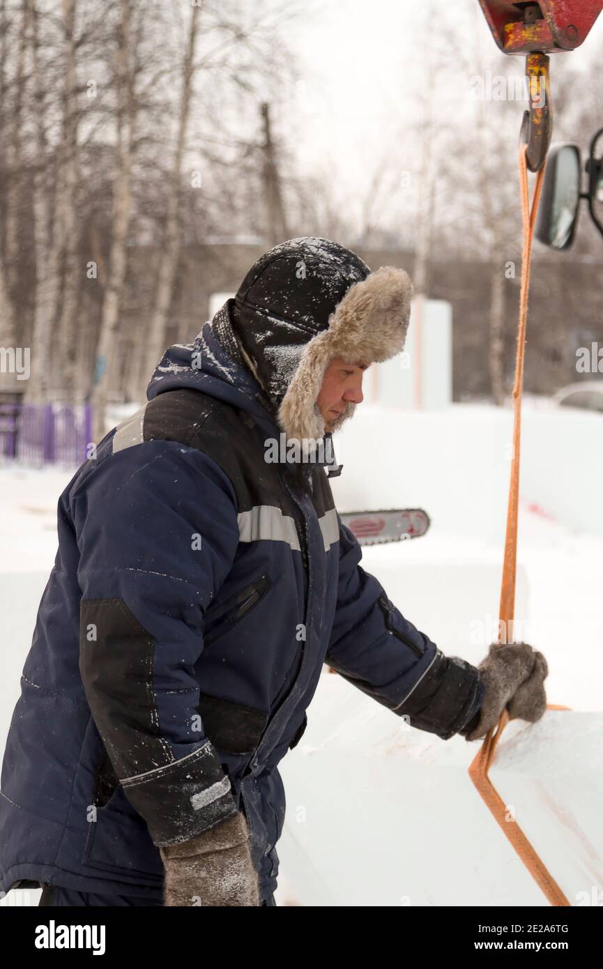 A slinger in a hat with light fur in a blue winter jacket assembling ...