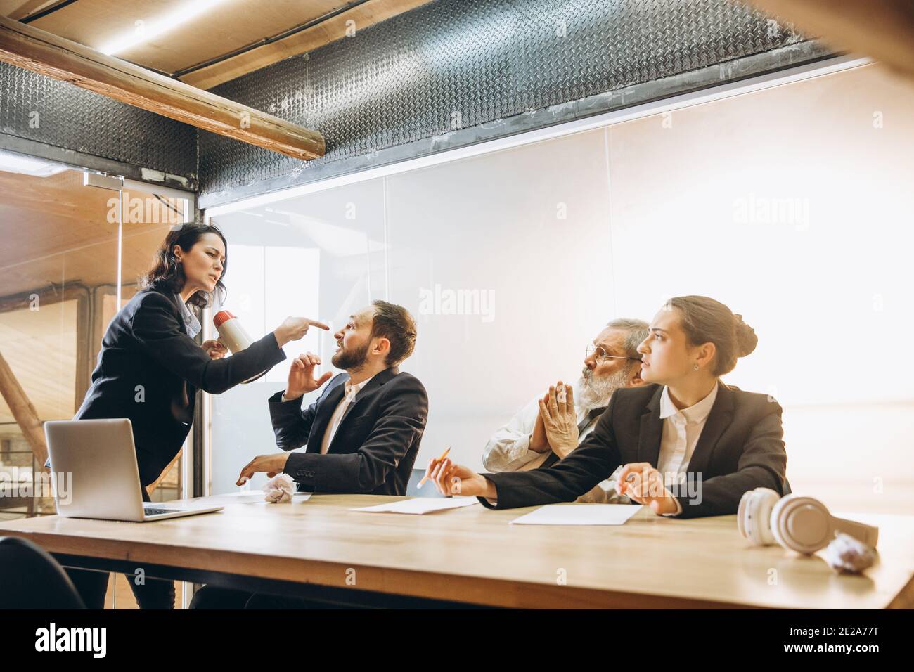 Dangerous. Angry boss with megaphone screaming at employees in office ...