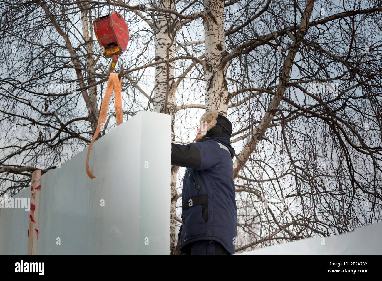 A slinger in a hat with light fur in a blue winter jacket assembling ...
