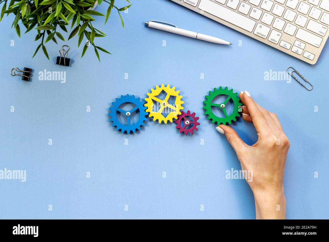 Hand puts a gear into one working mechanism. Teamwork and collaboration ...