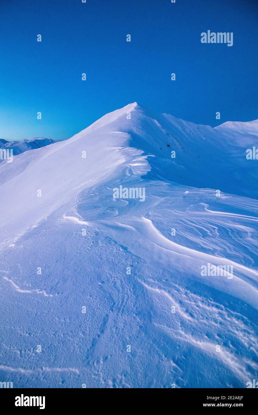 Vertical shot of mountains covered in snow under a bright sky Stock ...