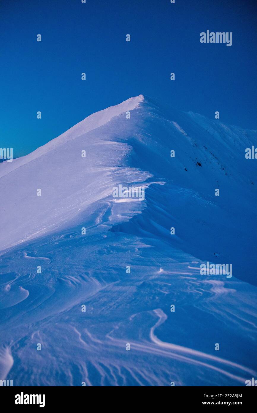 Vertical shot of mountains covered in snow under a bright sky Stock ...