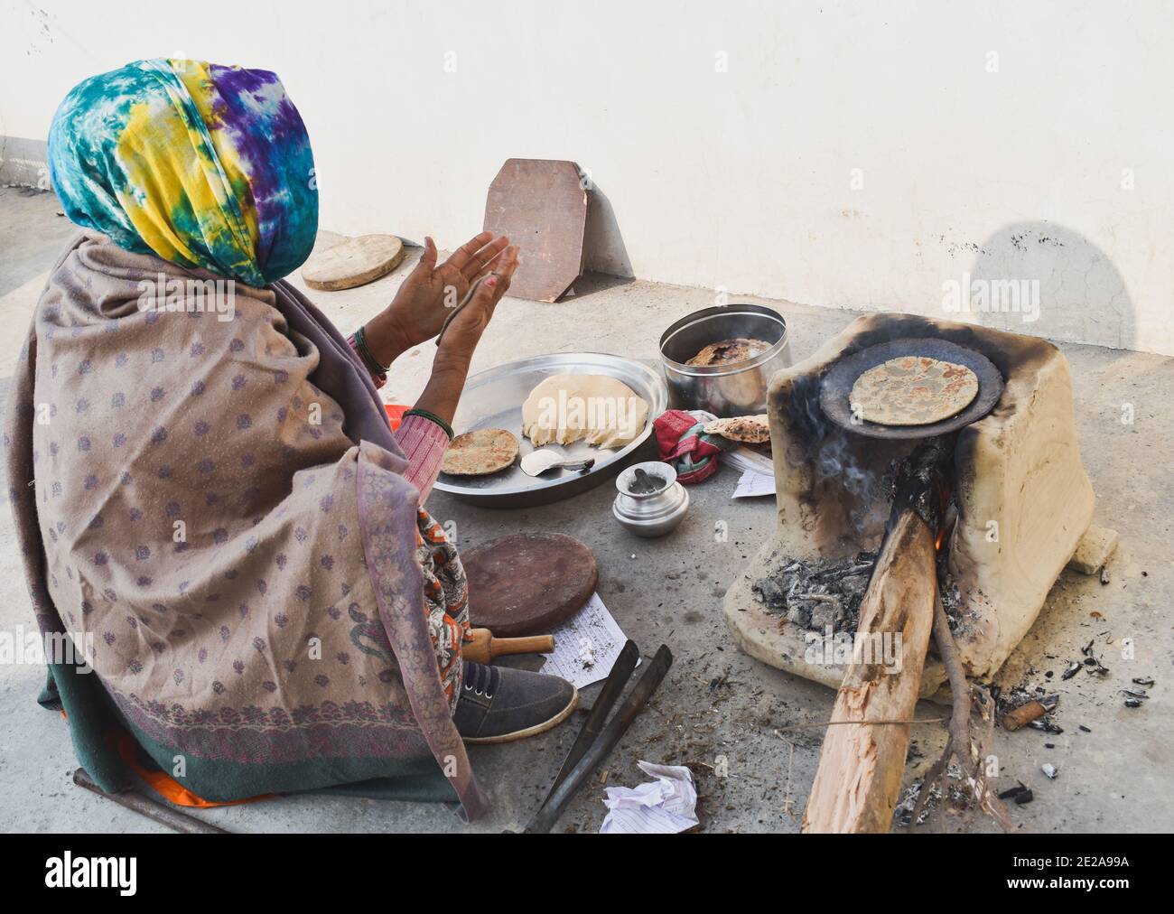Rural Indian female preparing chapati in a traditional way on a wood ...