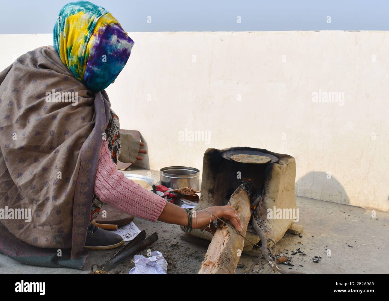 Rural Indian female preparing chapati in a traditional way on a wood ...