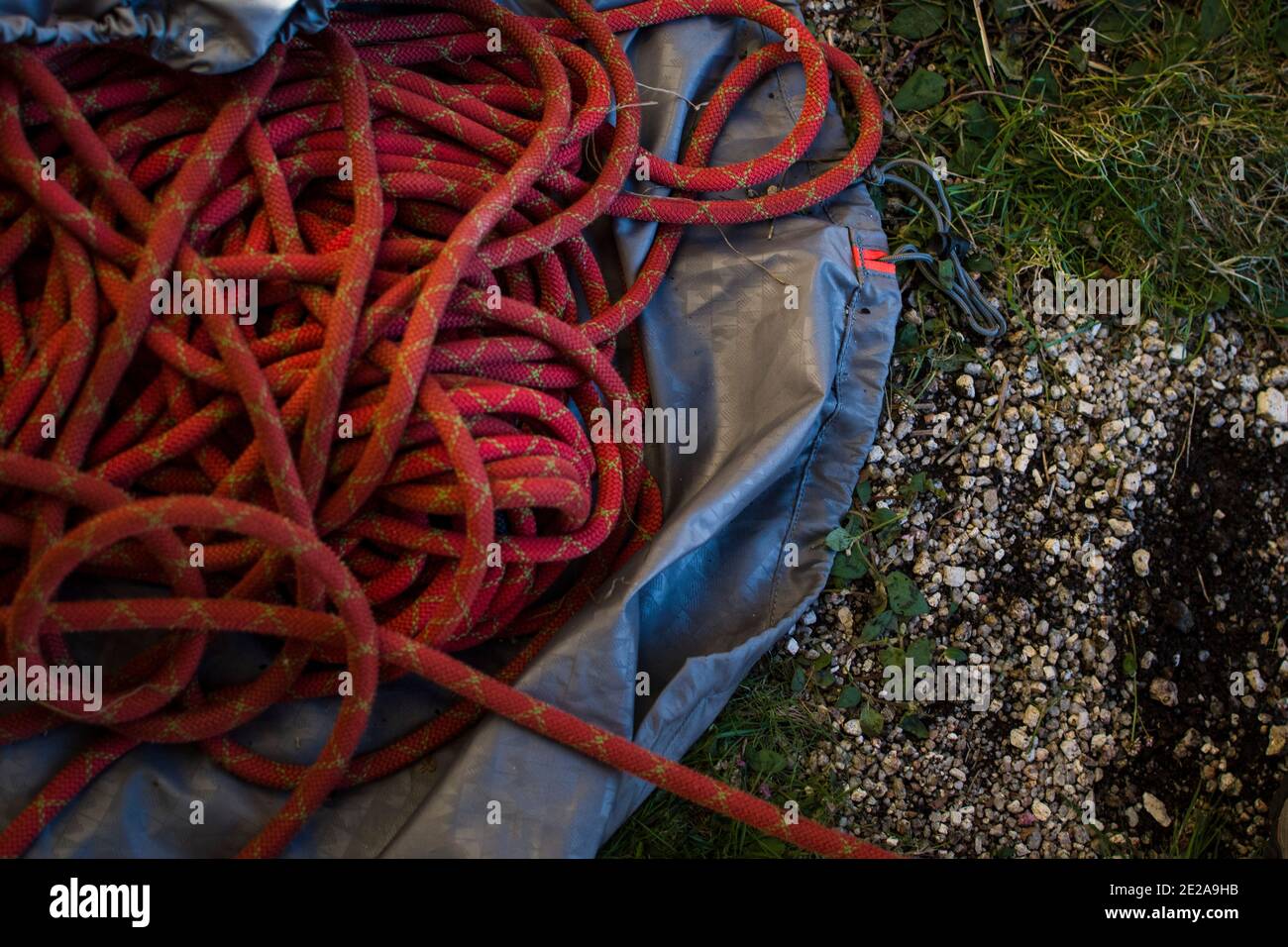 Red rock climbing rope laying tangled on the ground before belaying ...