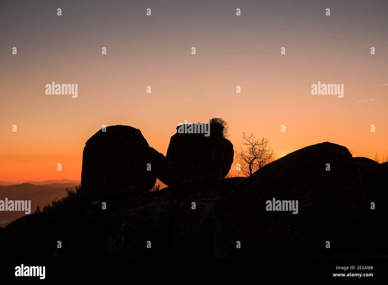 Two big stone rocks leaning against each other in backlight at sunset ...