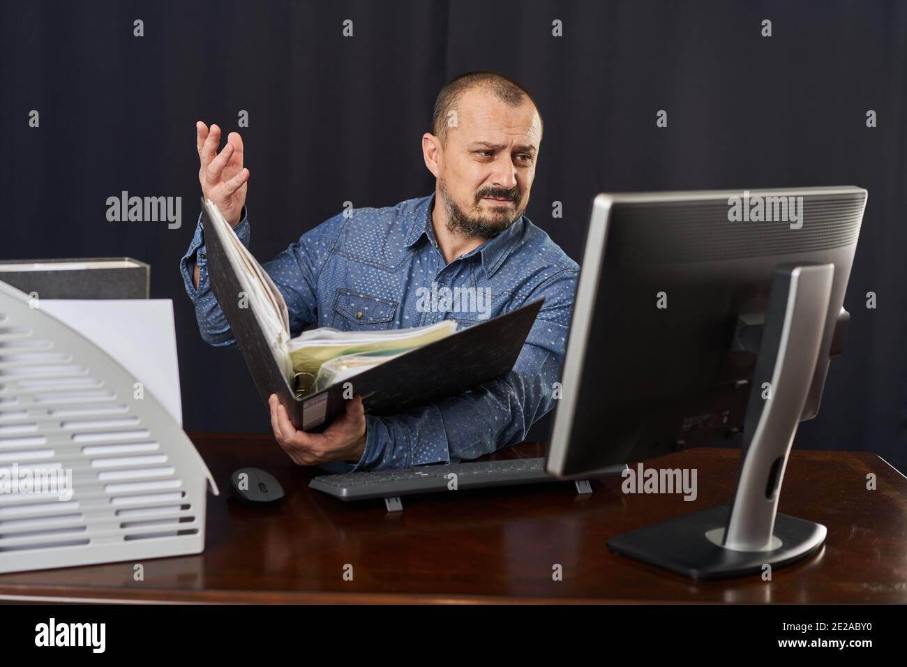 Angry and displeased office worker at his desk working with computer ...