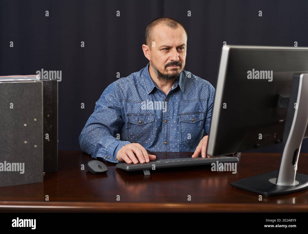Businessman at his desk working on the computer alongside office ...