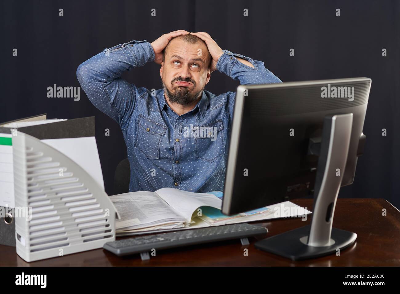 Angry and displeased office worker at his desk working with computer ...