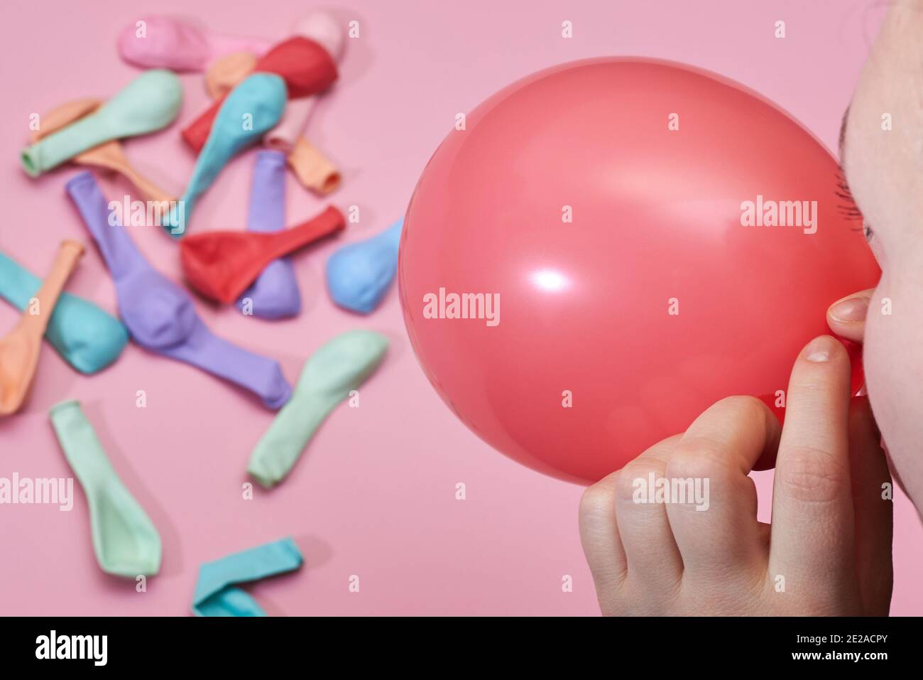 Woman starts to inflate a balloon on a pink background Stock Photo - Alamy