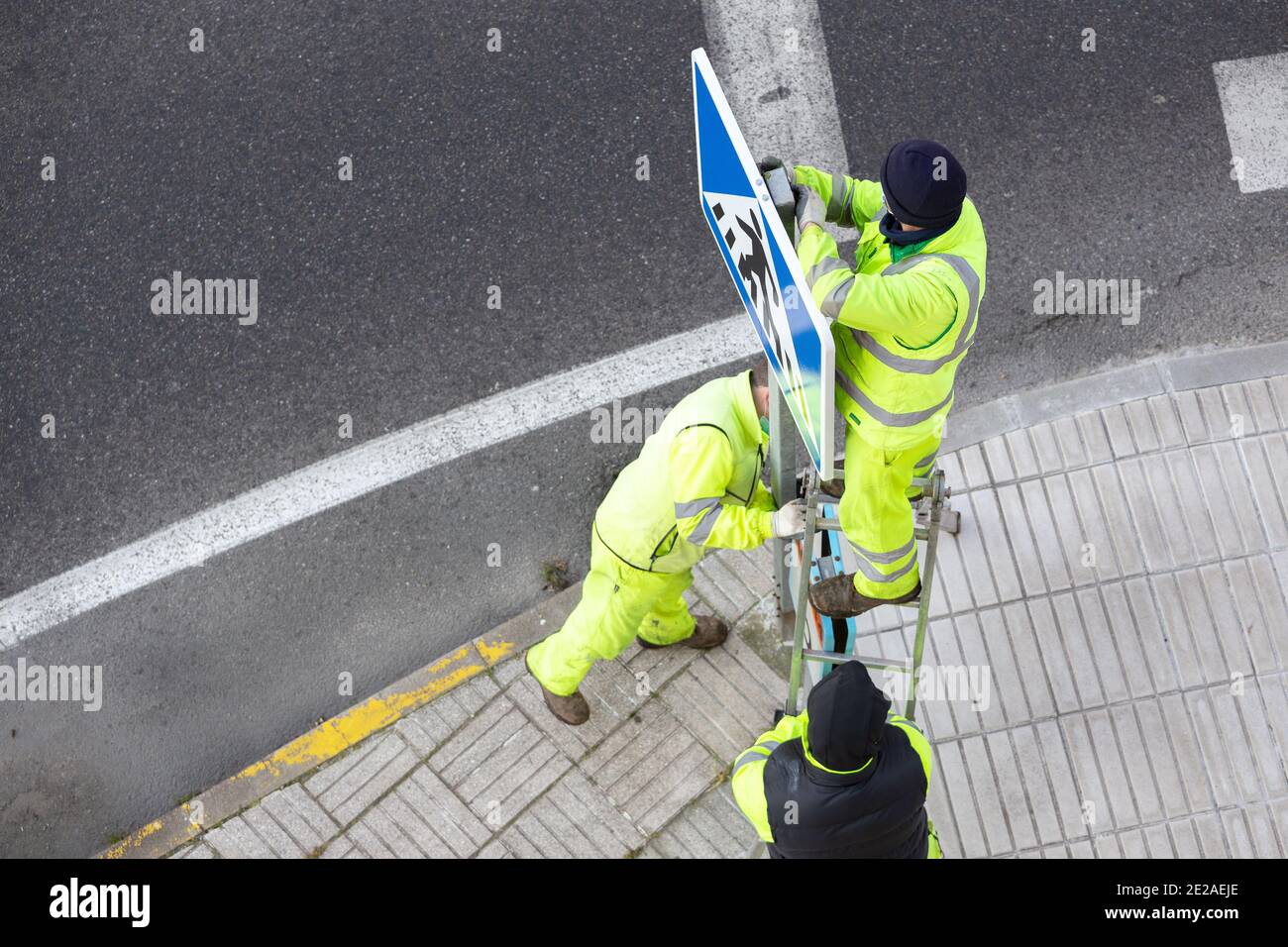 Workers installing a new road sign on street sidewalk. Public ...