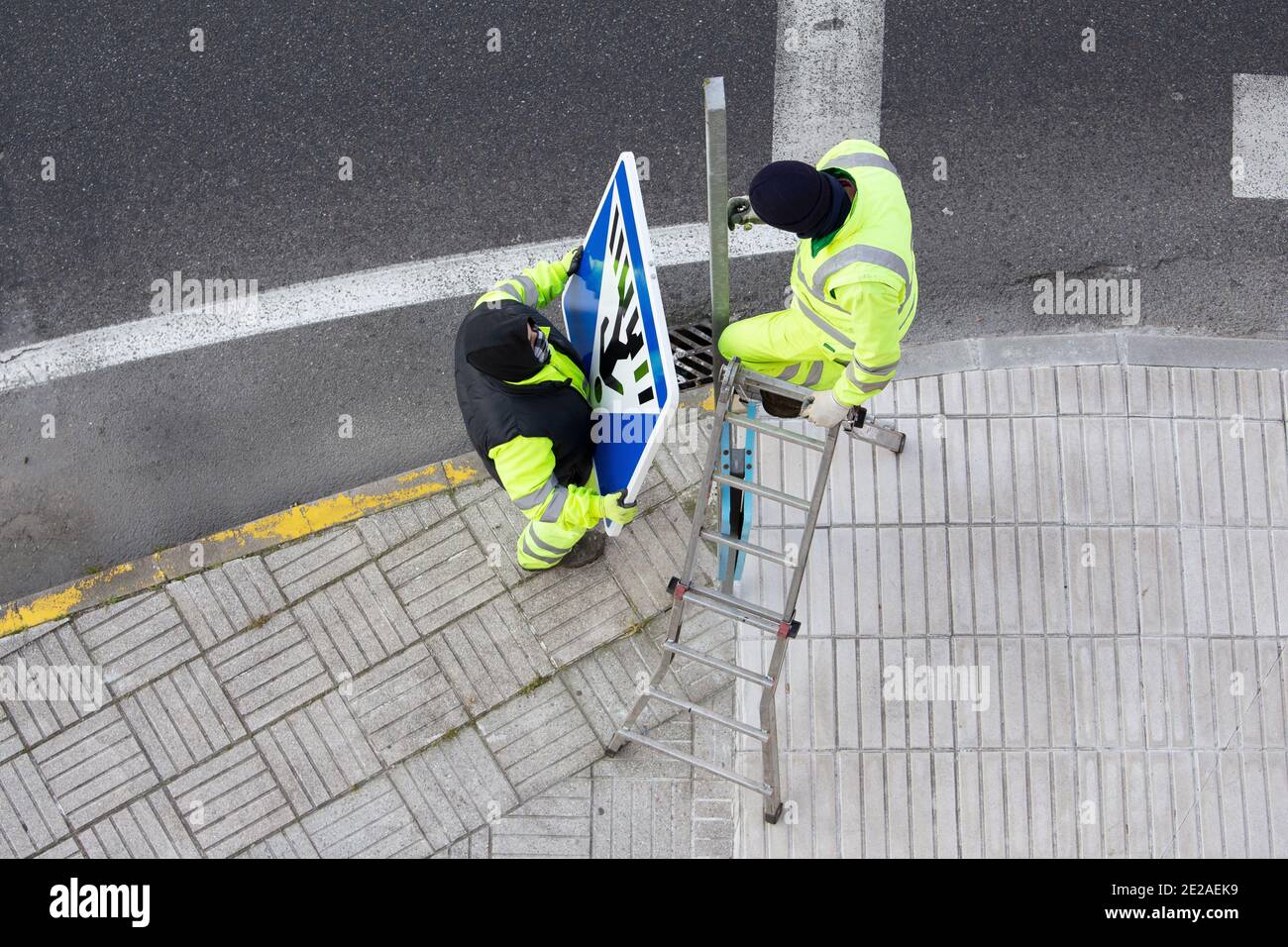 Workers installing a new road sign on street sidewalk. Public ...