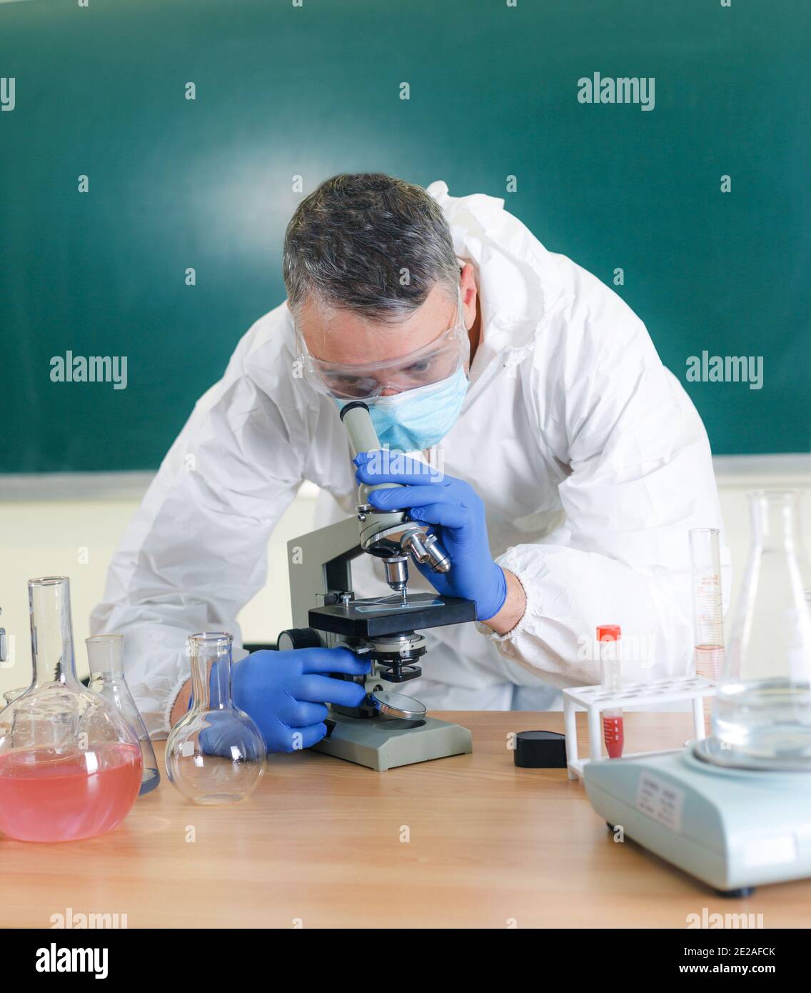 A young scientist studies the COVID-19 virus under a microscope in the ...
