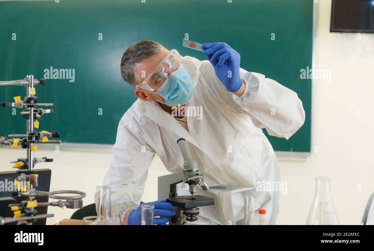 The scientist carefully examines the blood sample. He looks at the drop ...