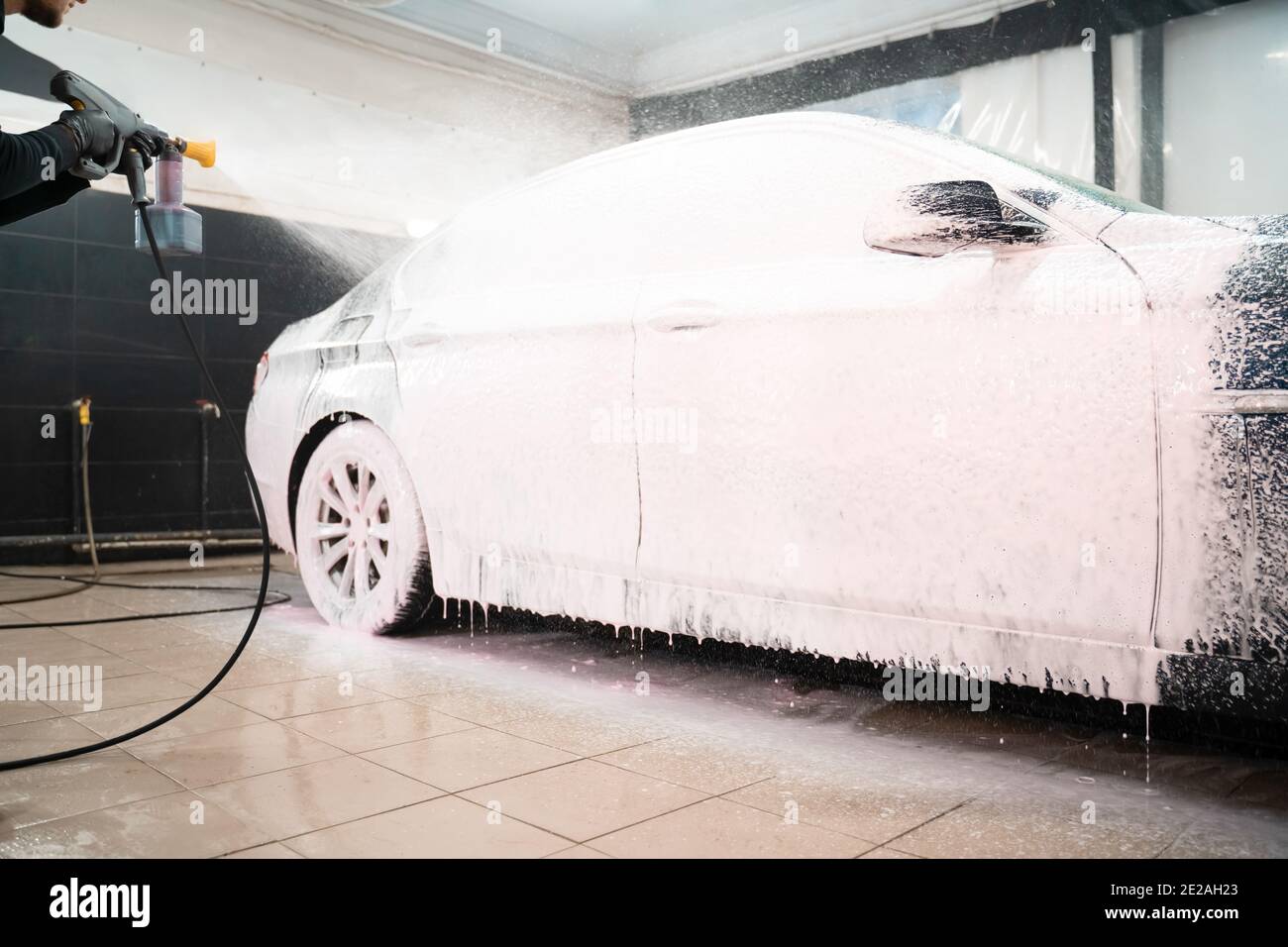 Car wash employee applies foam to the car. Professional auto wash Stock ...
