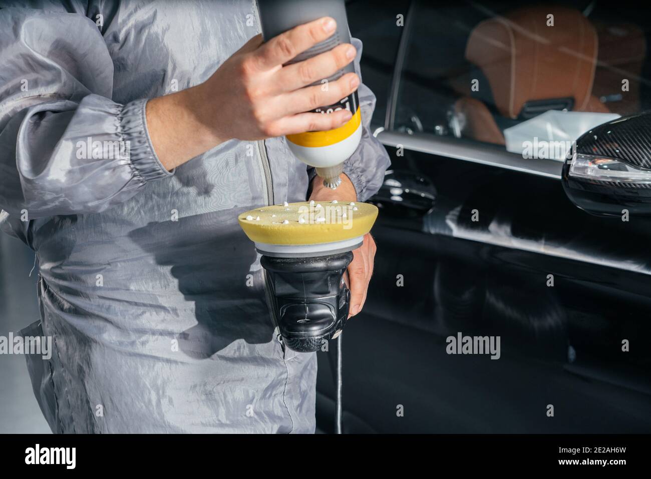 Worker polishing car with special grinder and wax from scratches at the ...