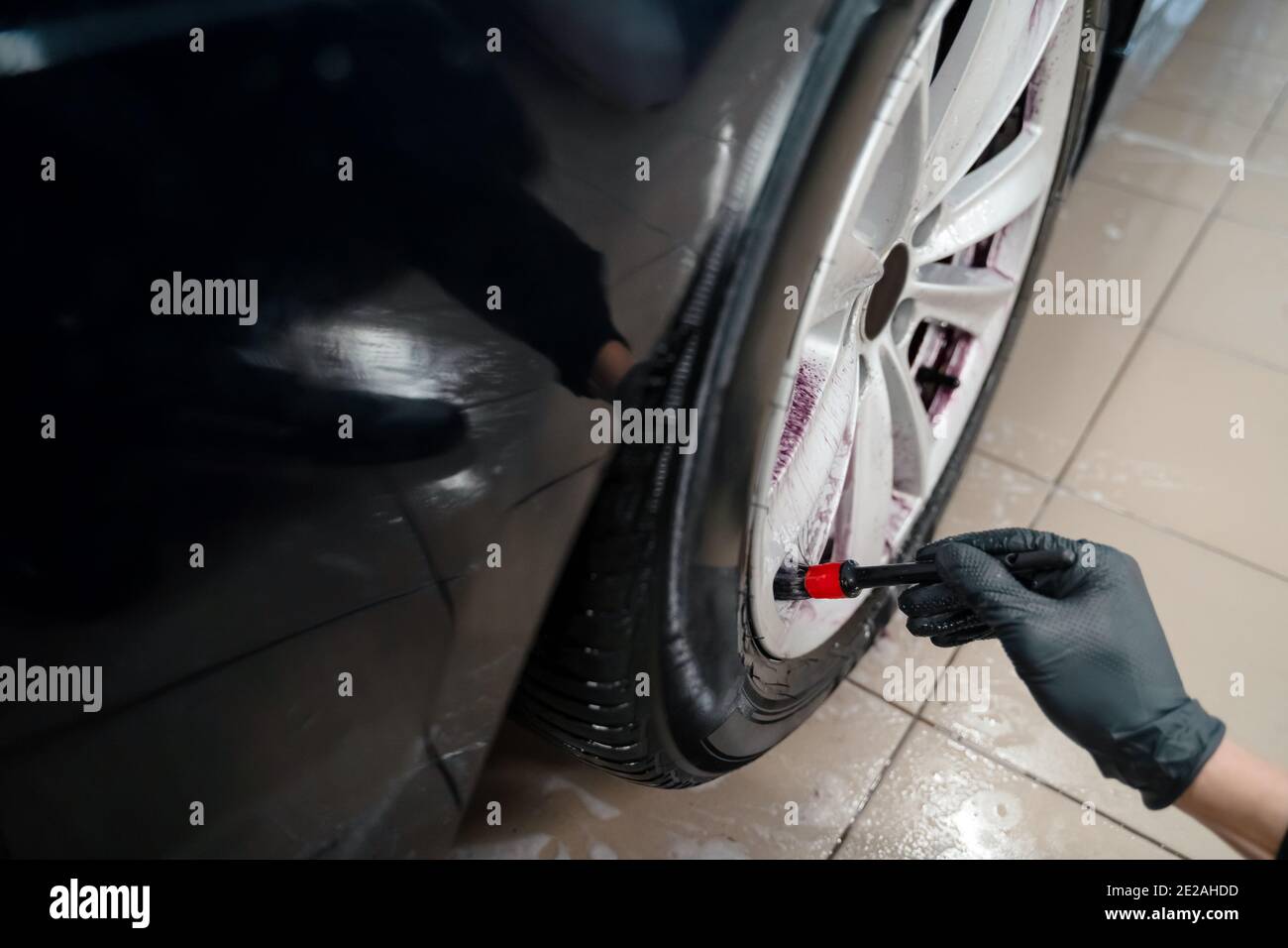 Detailing center worker cleans car wheels with brush. Vehicle wheel rim ...
