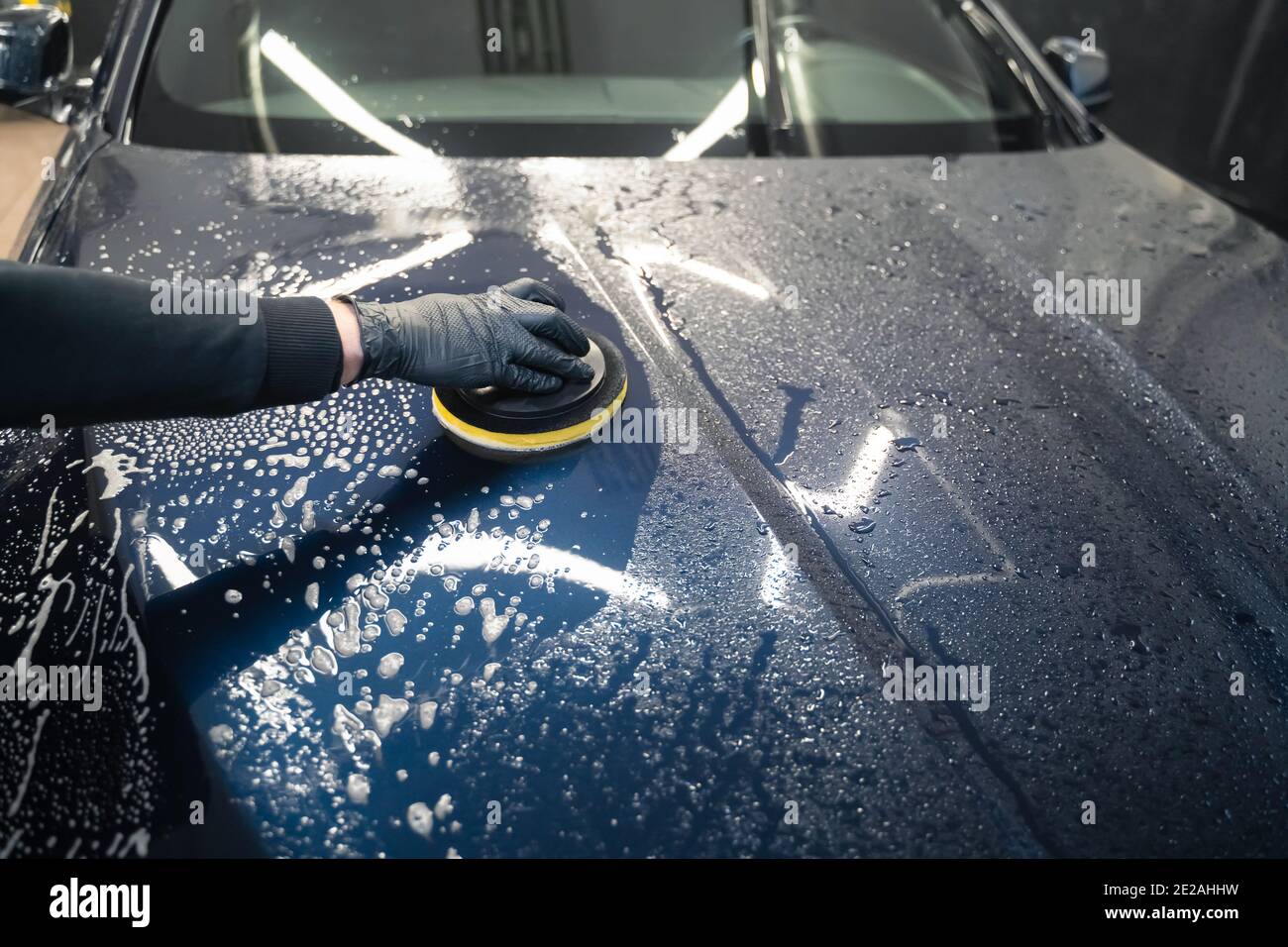 Man cleans car hood with circle sponge. Preparing auto for polishing ...
