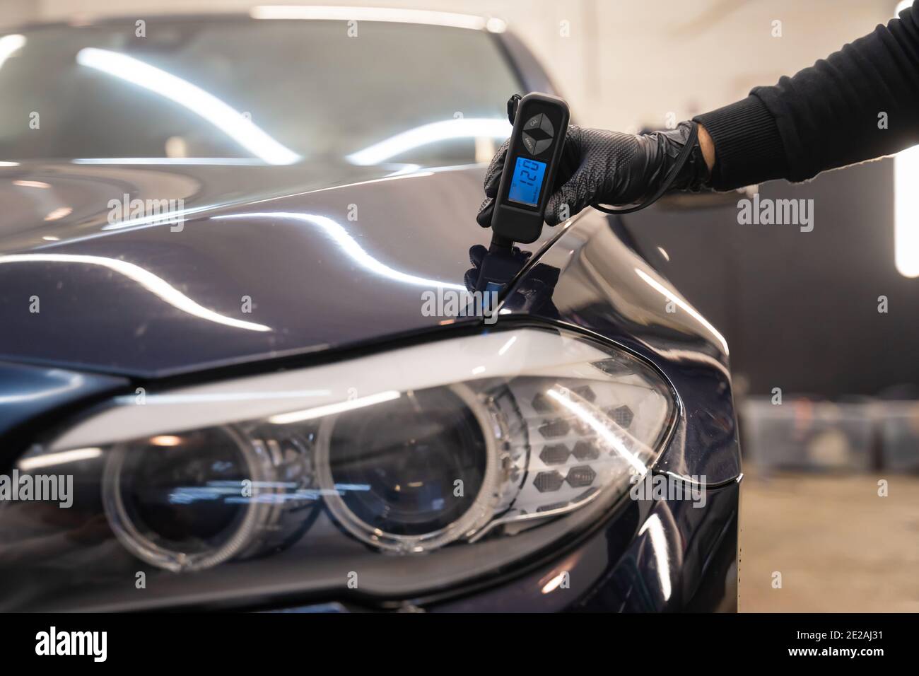Detailing worker checks the condition of the paintwork with electronic ...