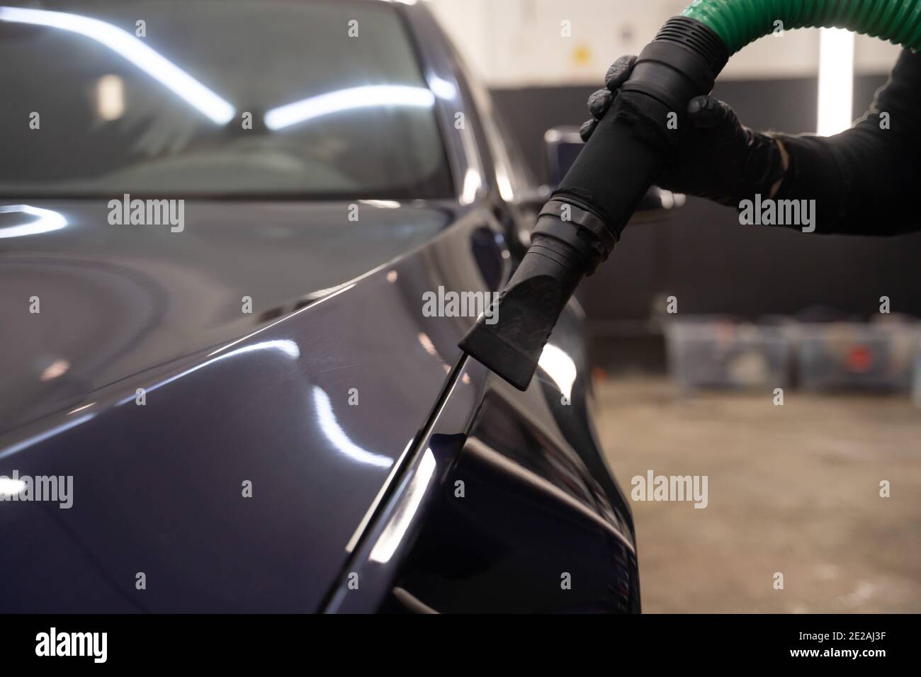 Car drying process after washing. Man with vacuum cleaner removes water ...