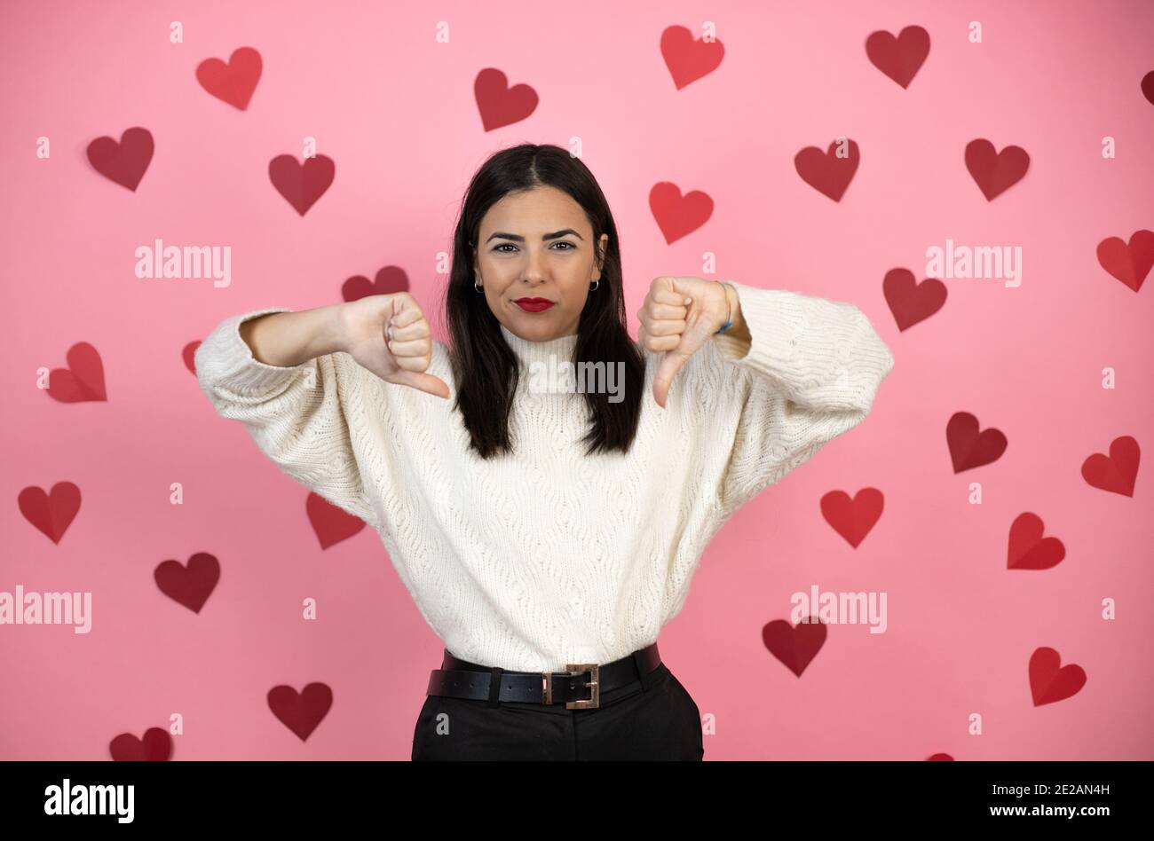 Young beautiful woman over pink background with harts with angry face ...