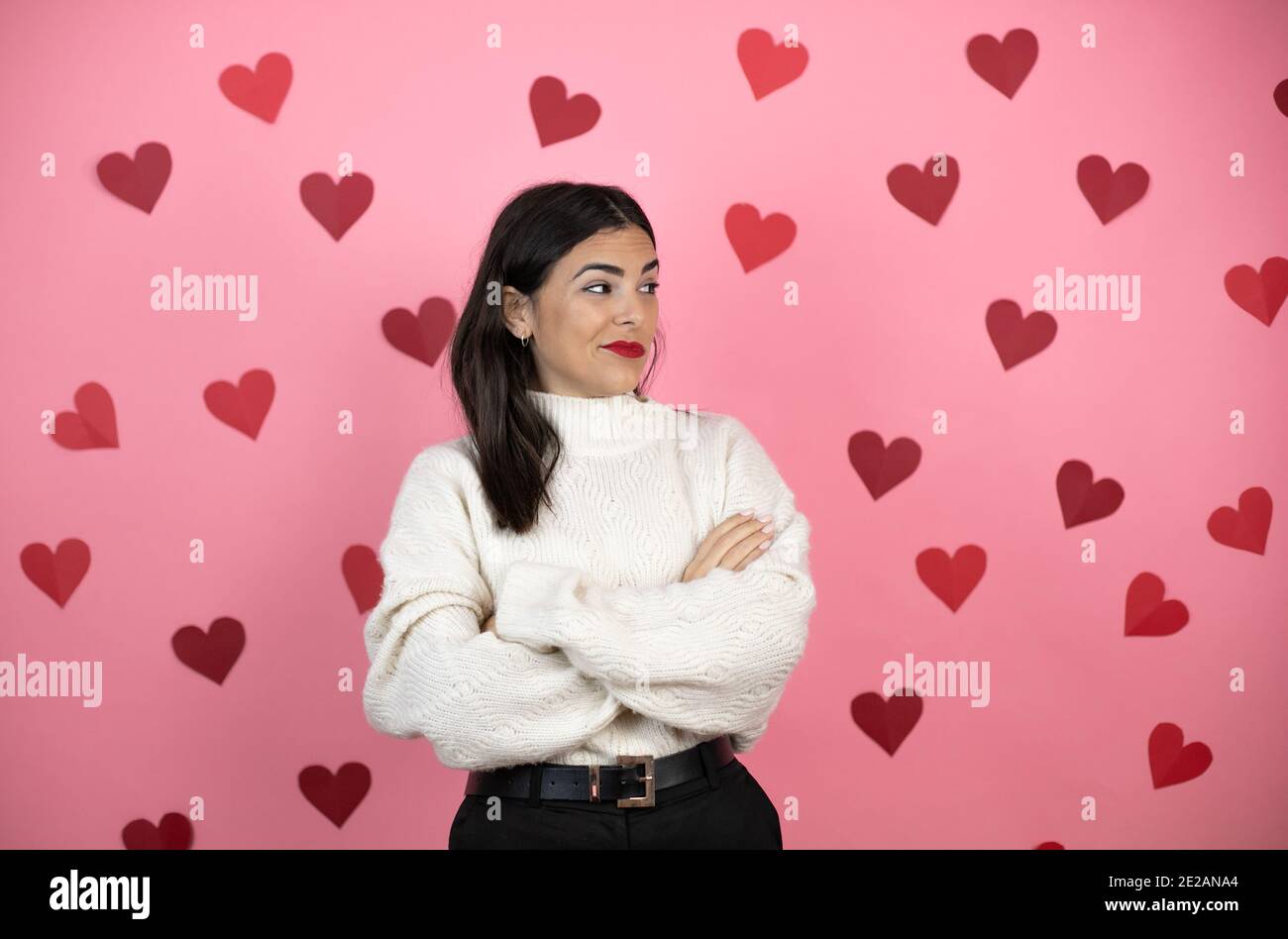 Young beautiful woman over pink background with harts thinking looking ...