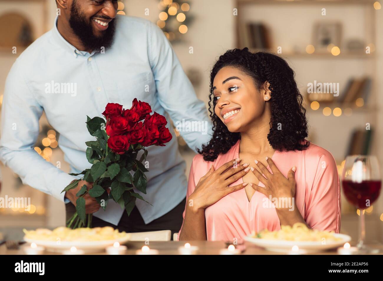 Young black man giving red roses to excited woman Stock Photo - Alamy