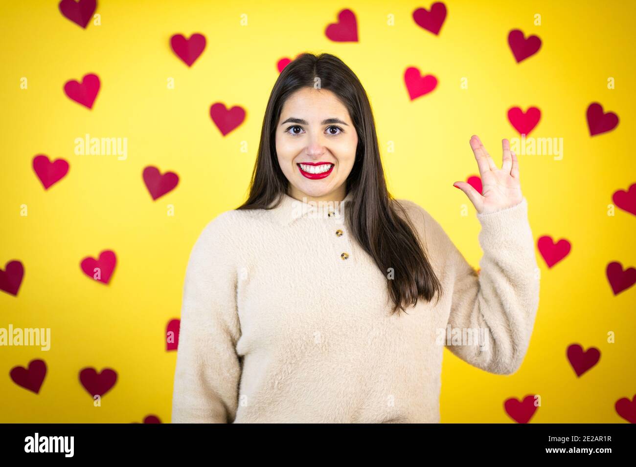Young caucasian woman over yellow background with red hearts doing star ...