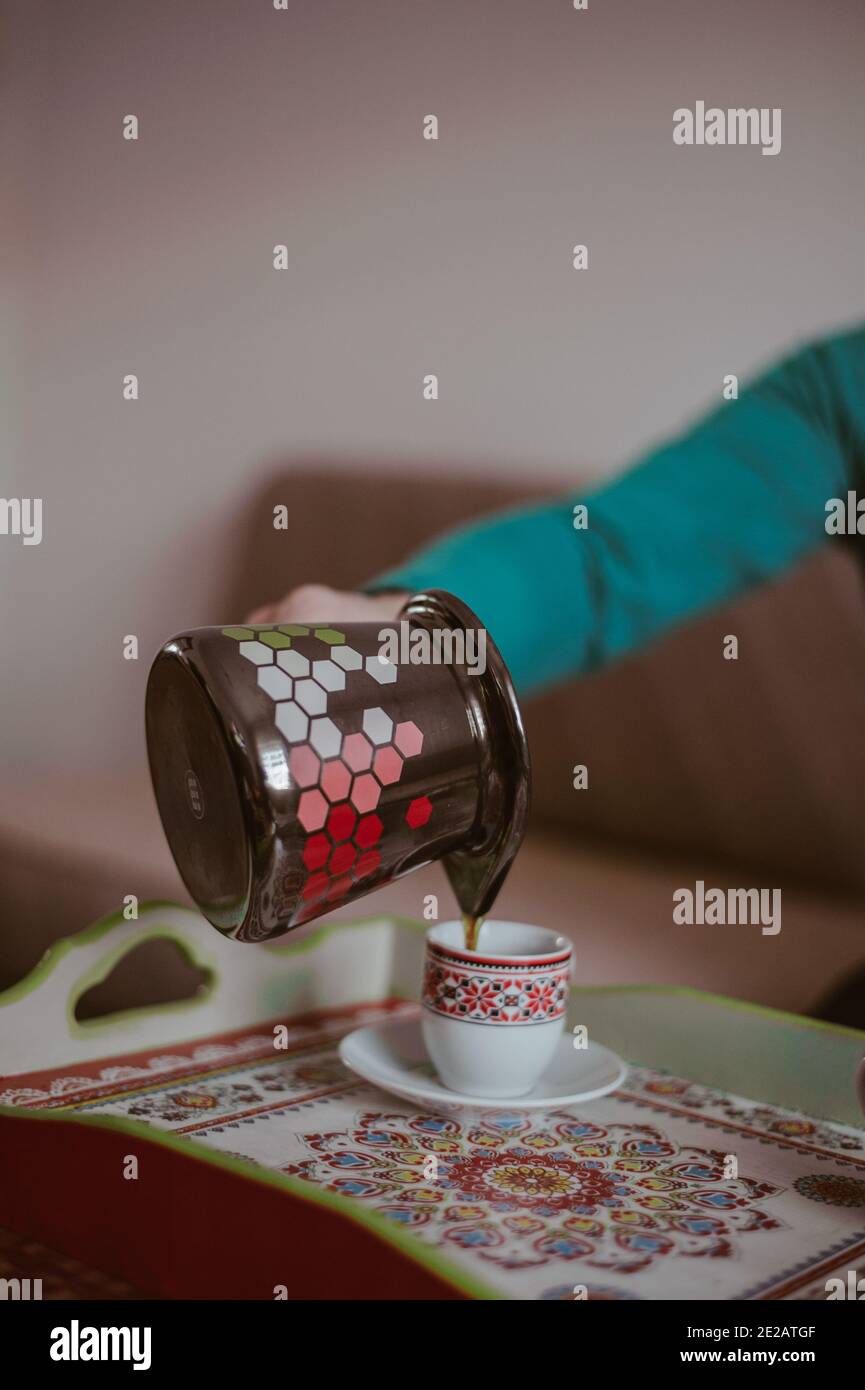 Vertical shot of someone's hand filling coffee from a coffee cezve on ...