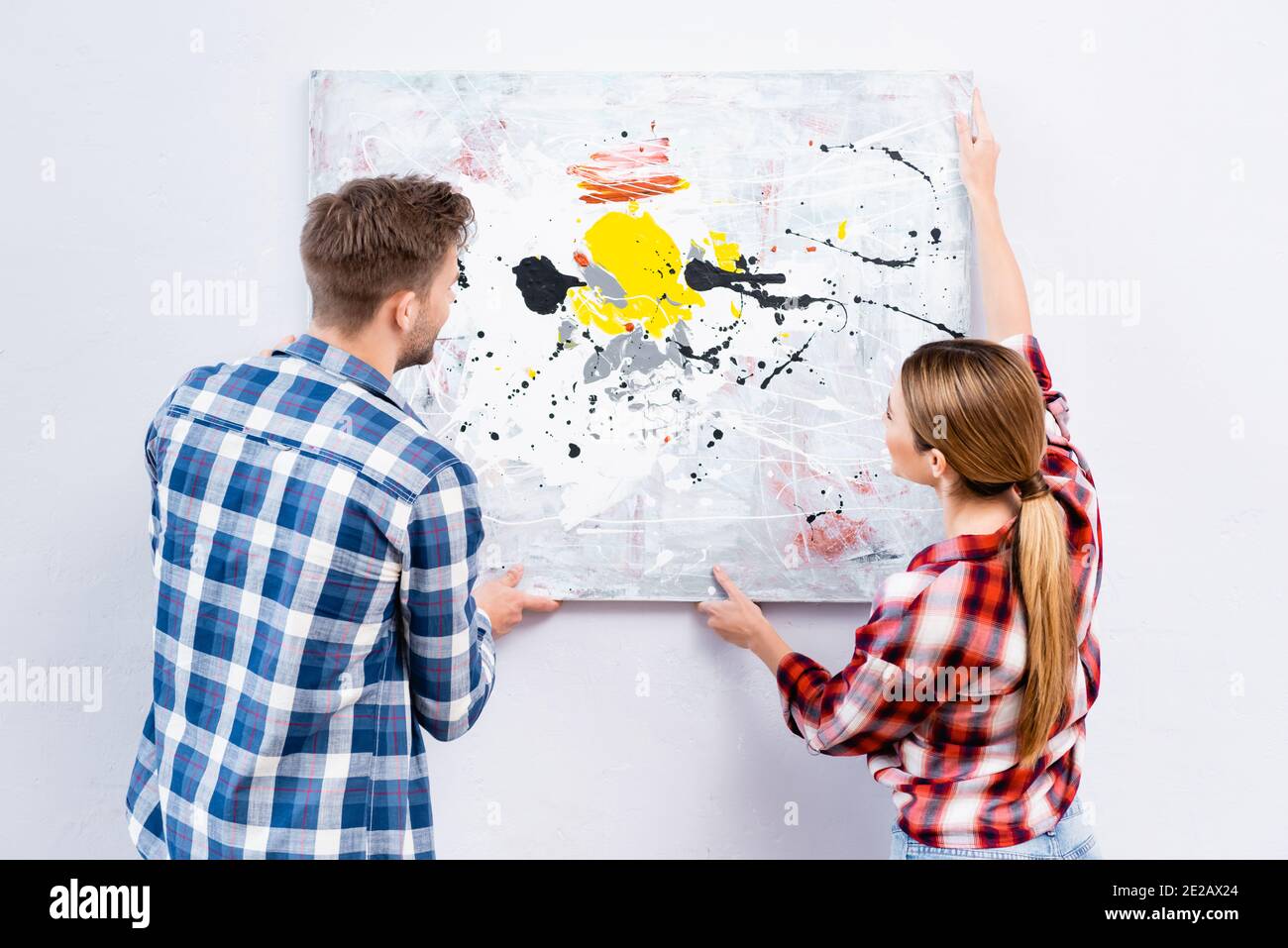 back view of young couple removing picture from wall isolated on white ...