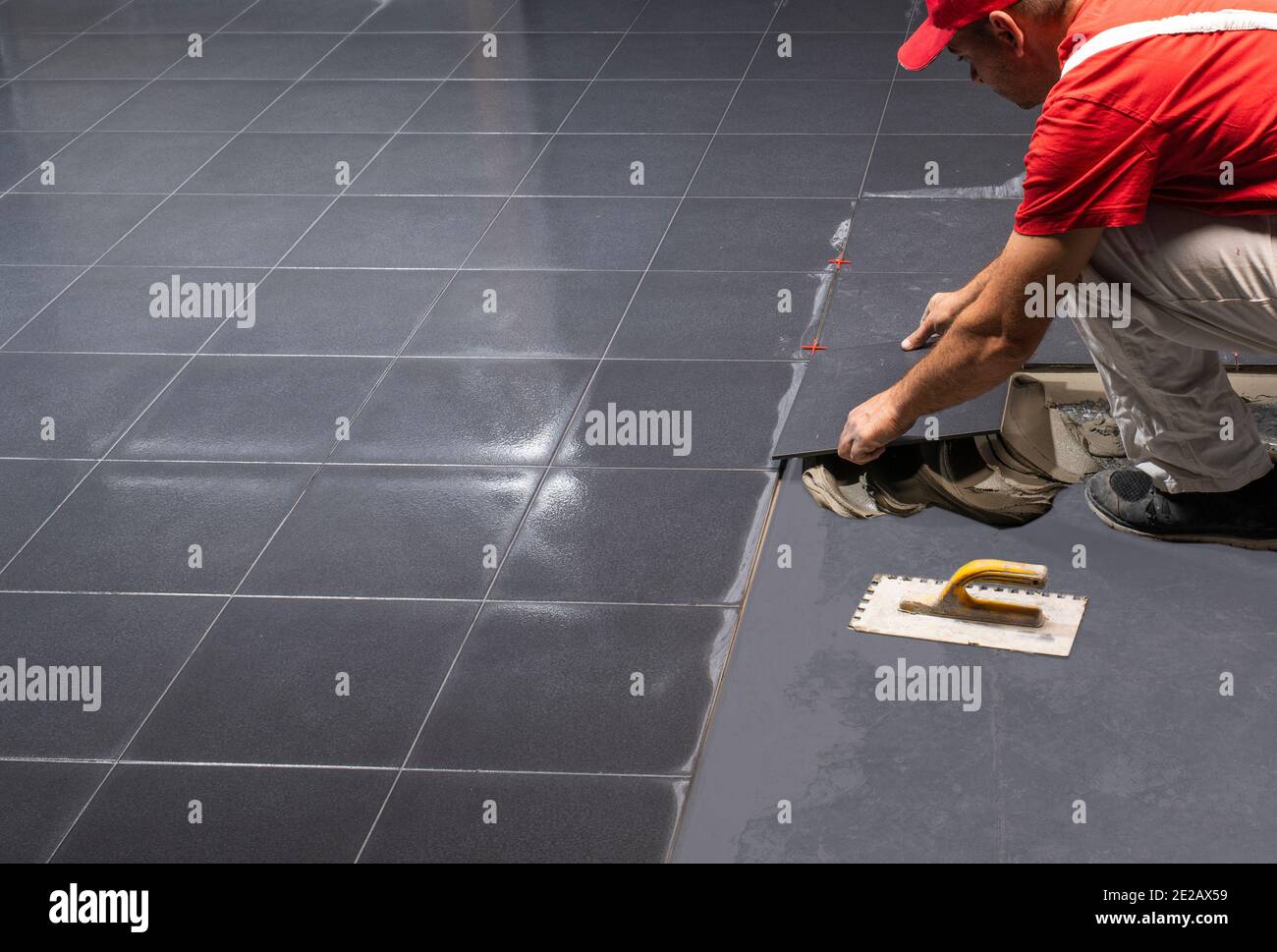 A construction worker putting on new floor tiles Stock Photo - Alamy