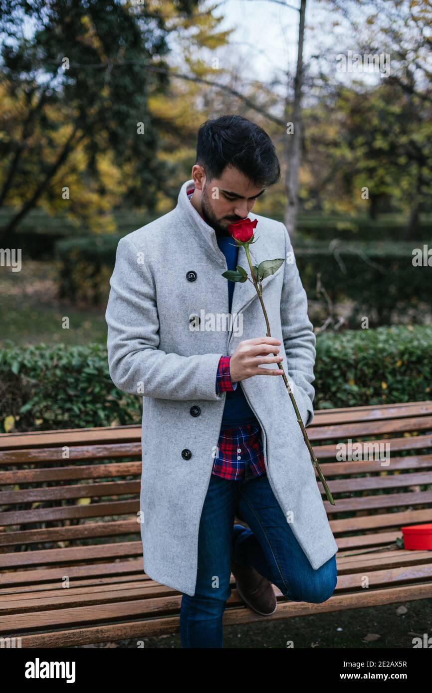 Vertical closeup of a male smelling a stem of red rose-concept ...