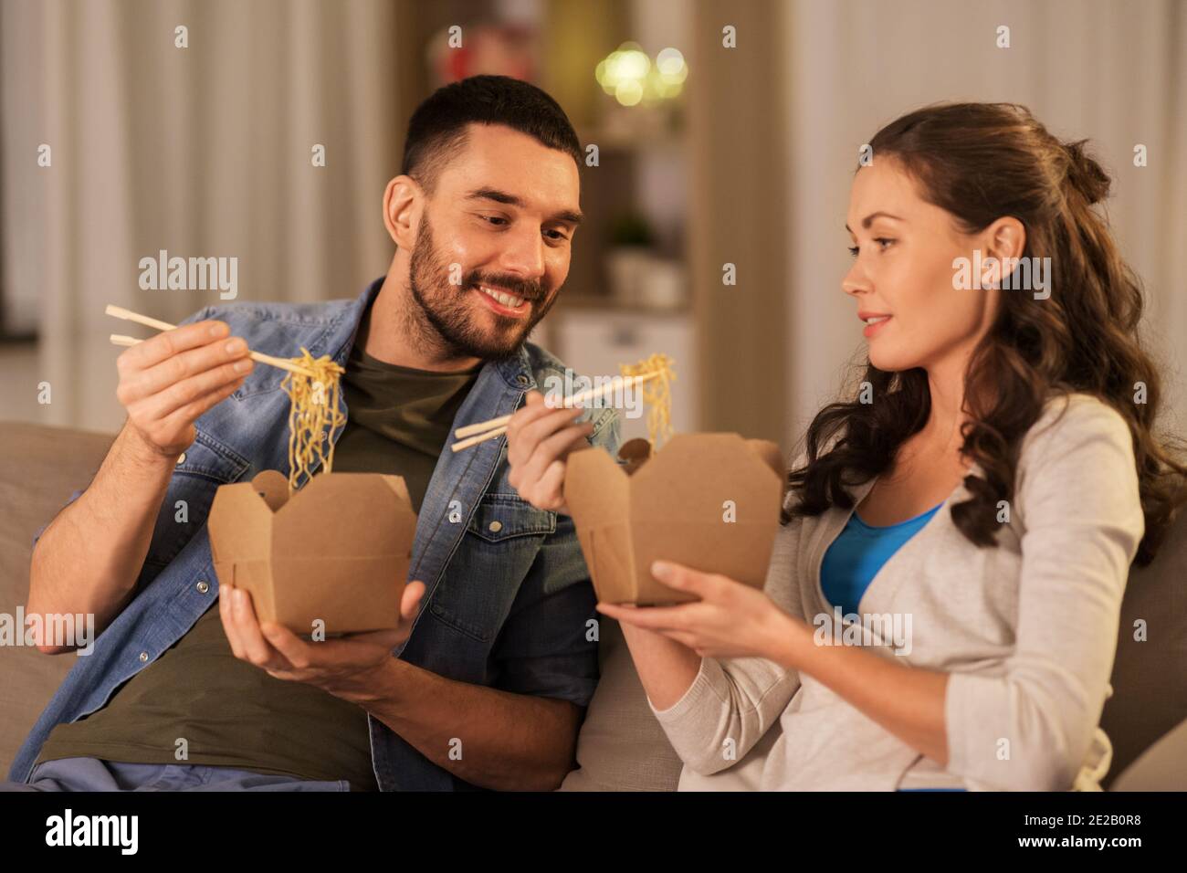happy couple eating takeaway noodles at home Stock Photo - Alamy
