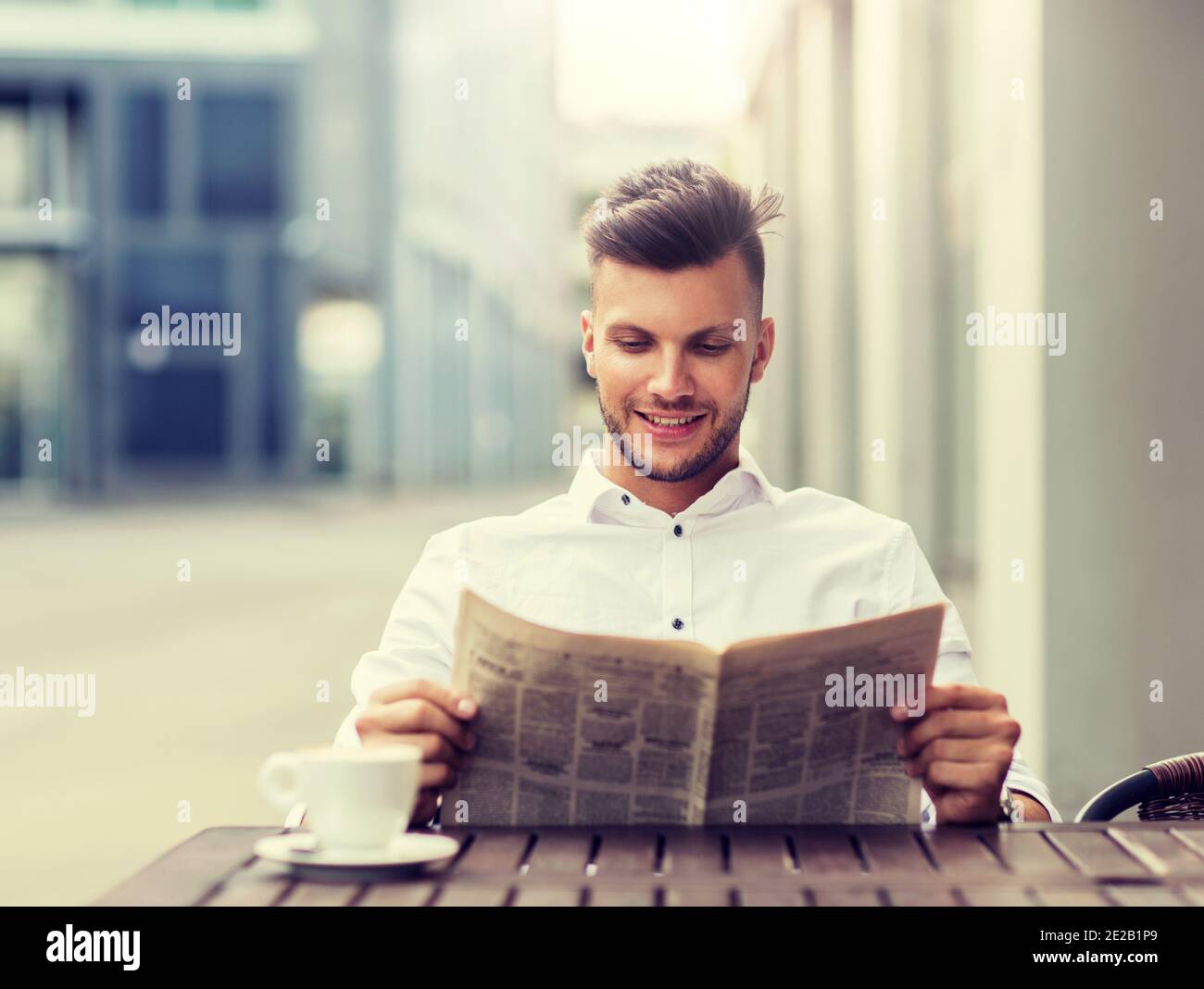 smiling man reading newspaper at city street cafe Stock Photo - Alamy
