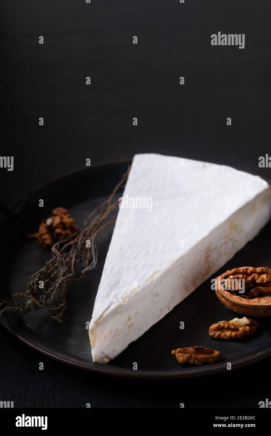 Food concept French Soft Brie cheese in rustic iron plate on black ...