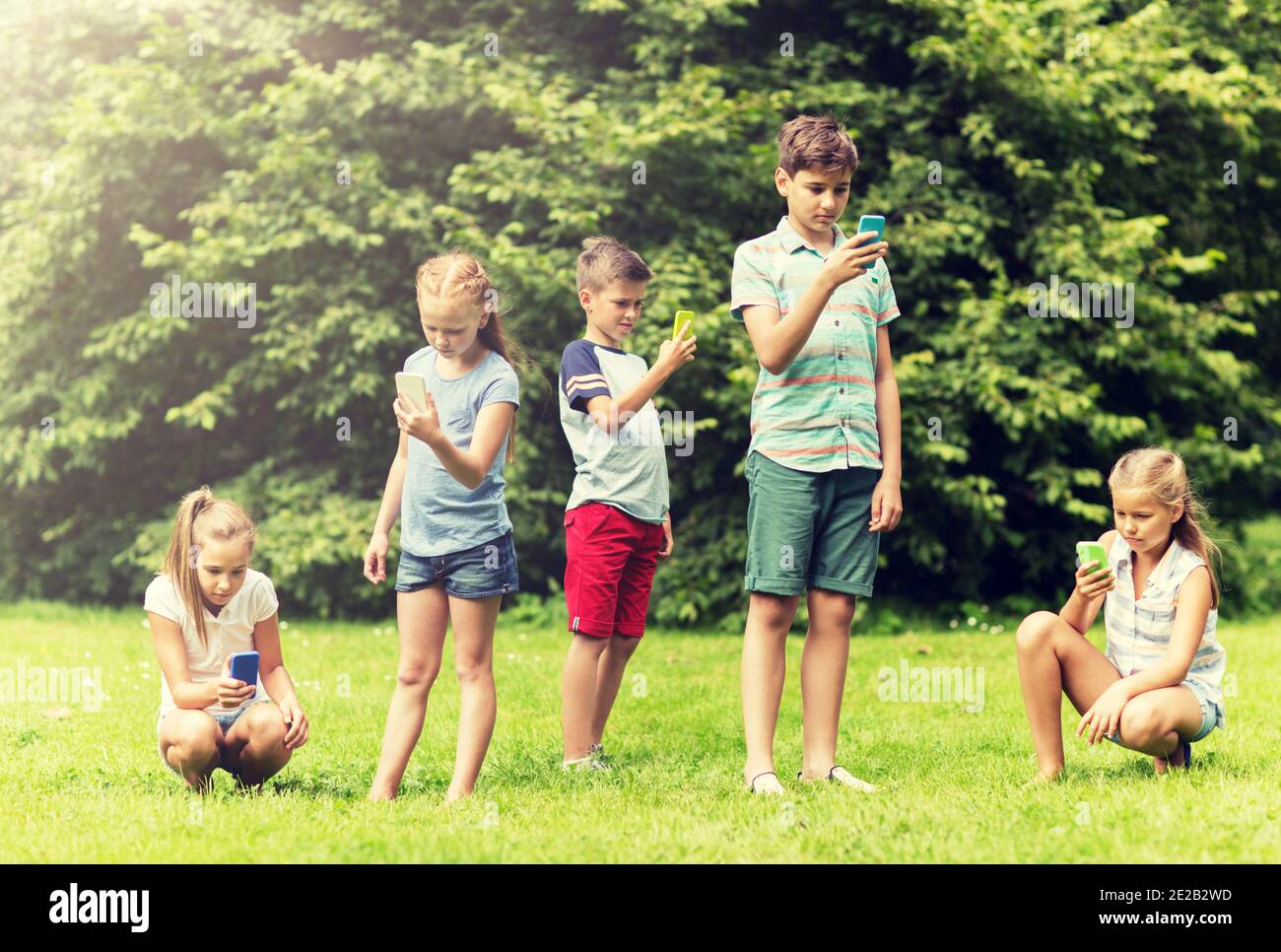 kids with smartphones playing game in summer park Stock Photo - Alamy