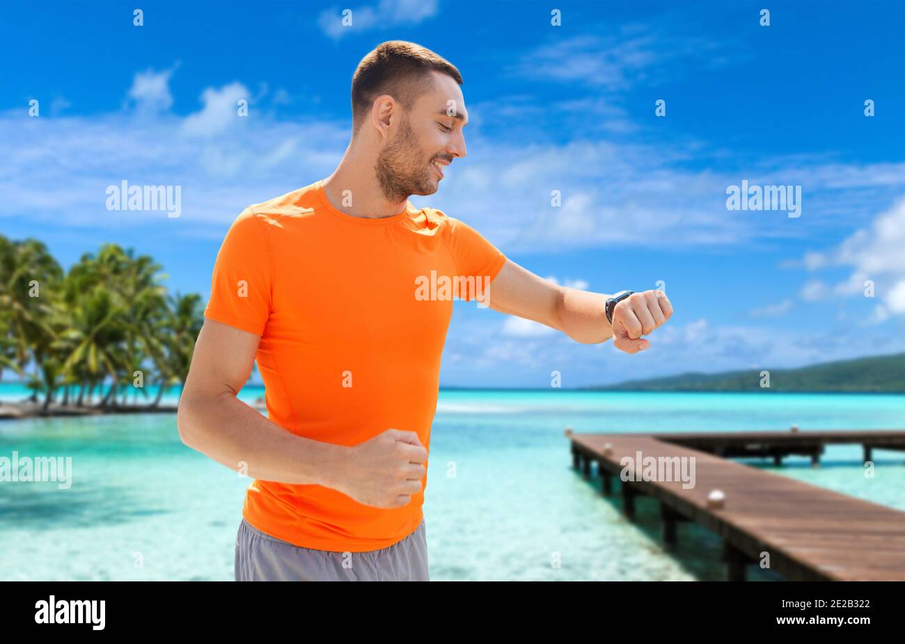 smiling man with smart watch running along beach Stock Photo - Alamy