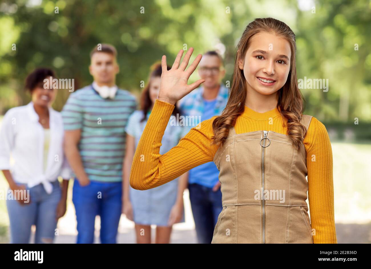 happy teenage girl waving hand over friends Stock Photo - Alamy