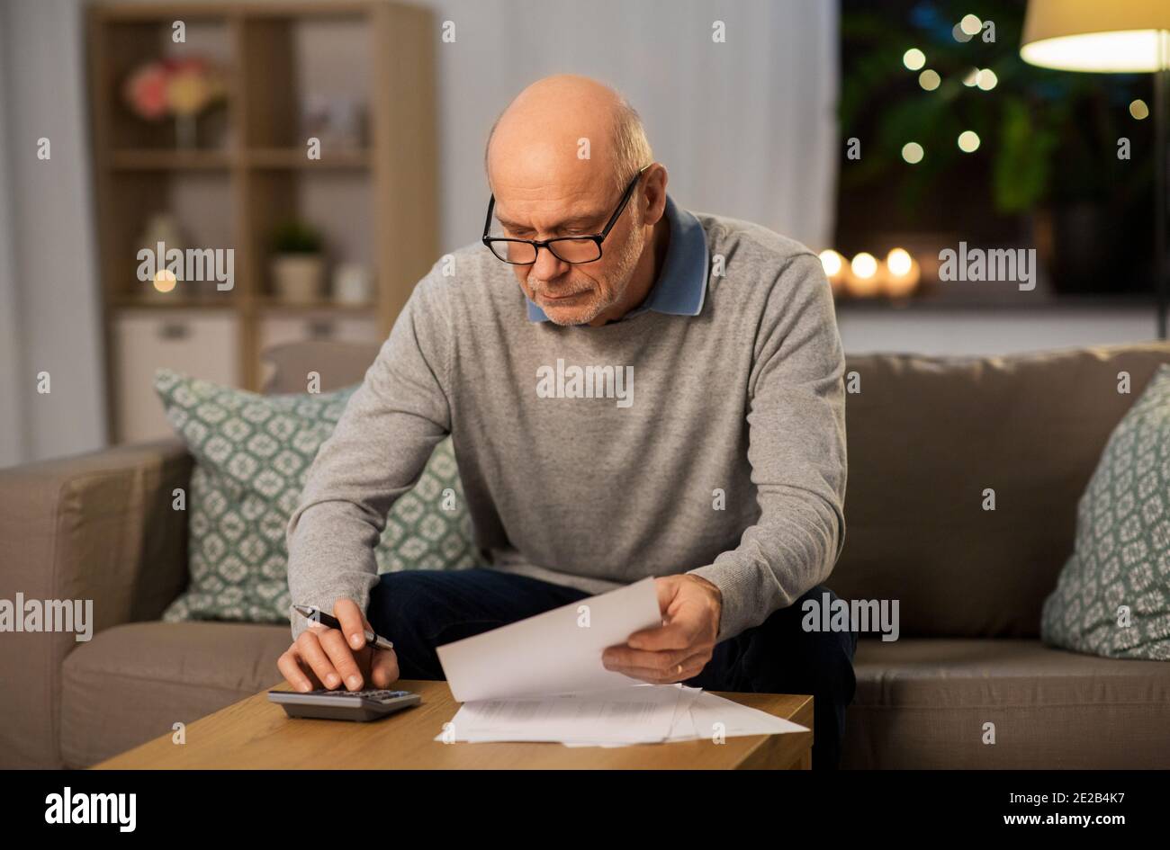 old man with bills counting on calculator at home Stock Photo - Alamy