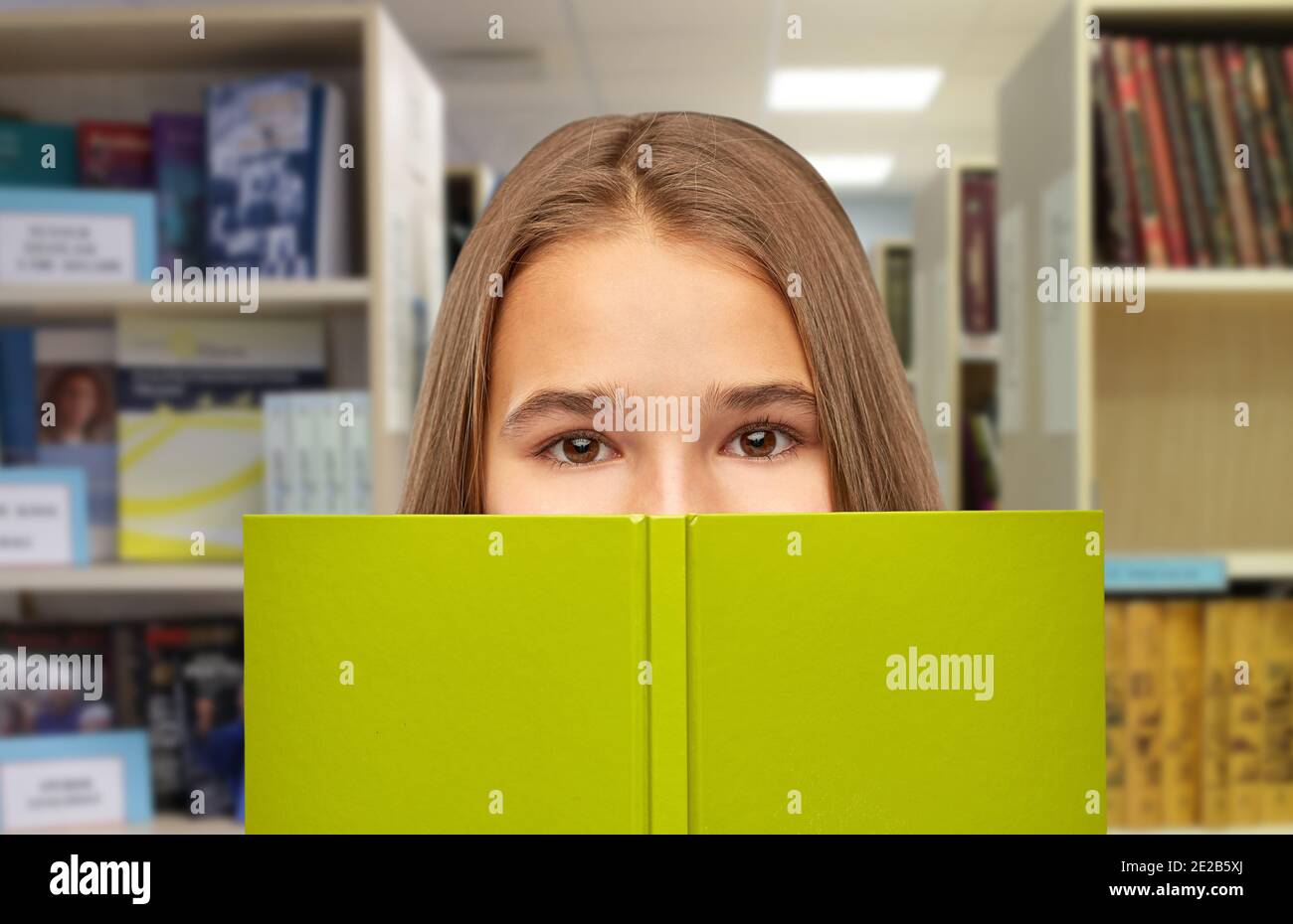 teenage student girl hiding over book at library Stock Photo - Alamy