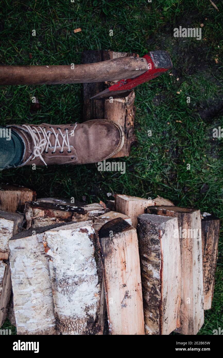 Vertical shot of a man cutting a wood log with an ax Stock Photo - Alamy