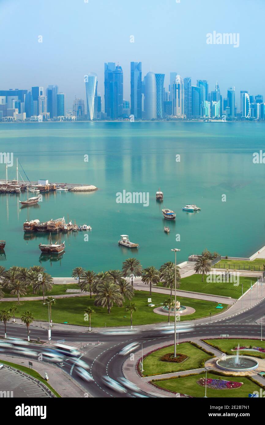Qatar, Doha, Traffic at roundabout, West Bay skyscrapers in background ...