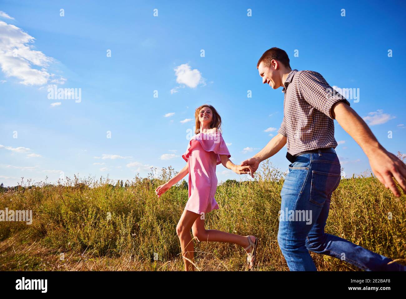 Shot of a young couple holding hands and running through the park ...