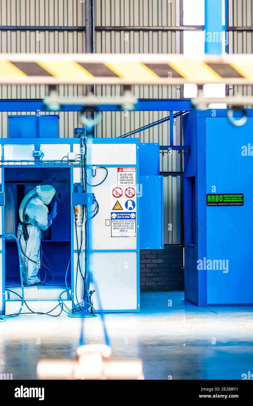 Vertical shot of a worker in a uniform adjusting a dangerous factory ...
