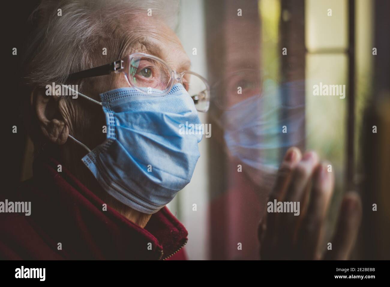 Old woman portrait at the window. Grandmother looking out on the street ...